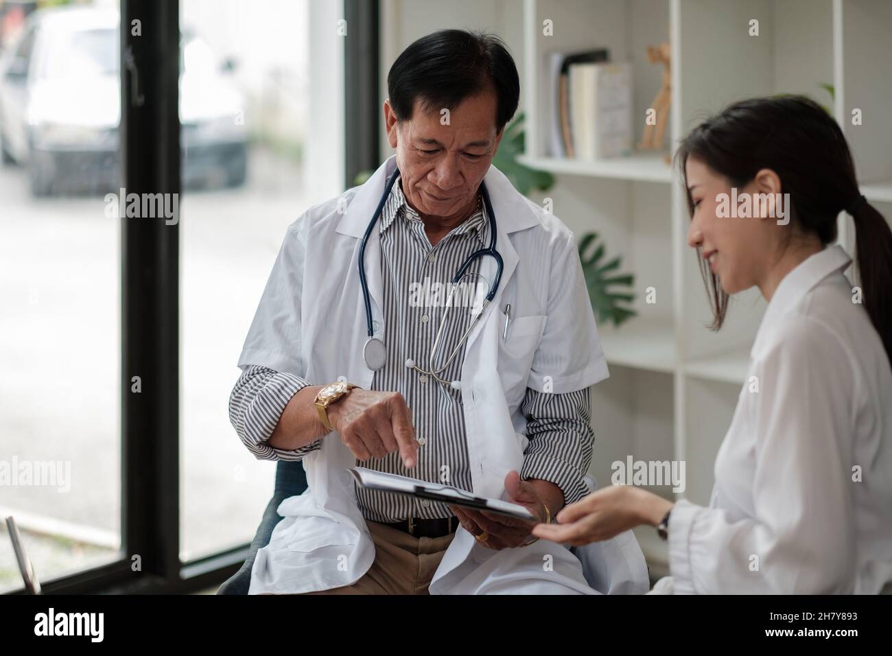 Senior asian doctor physician consulting young female patient, talking ...