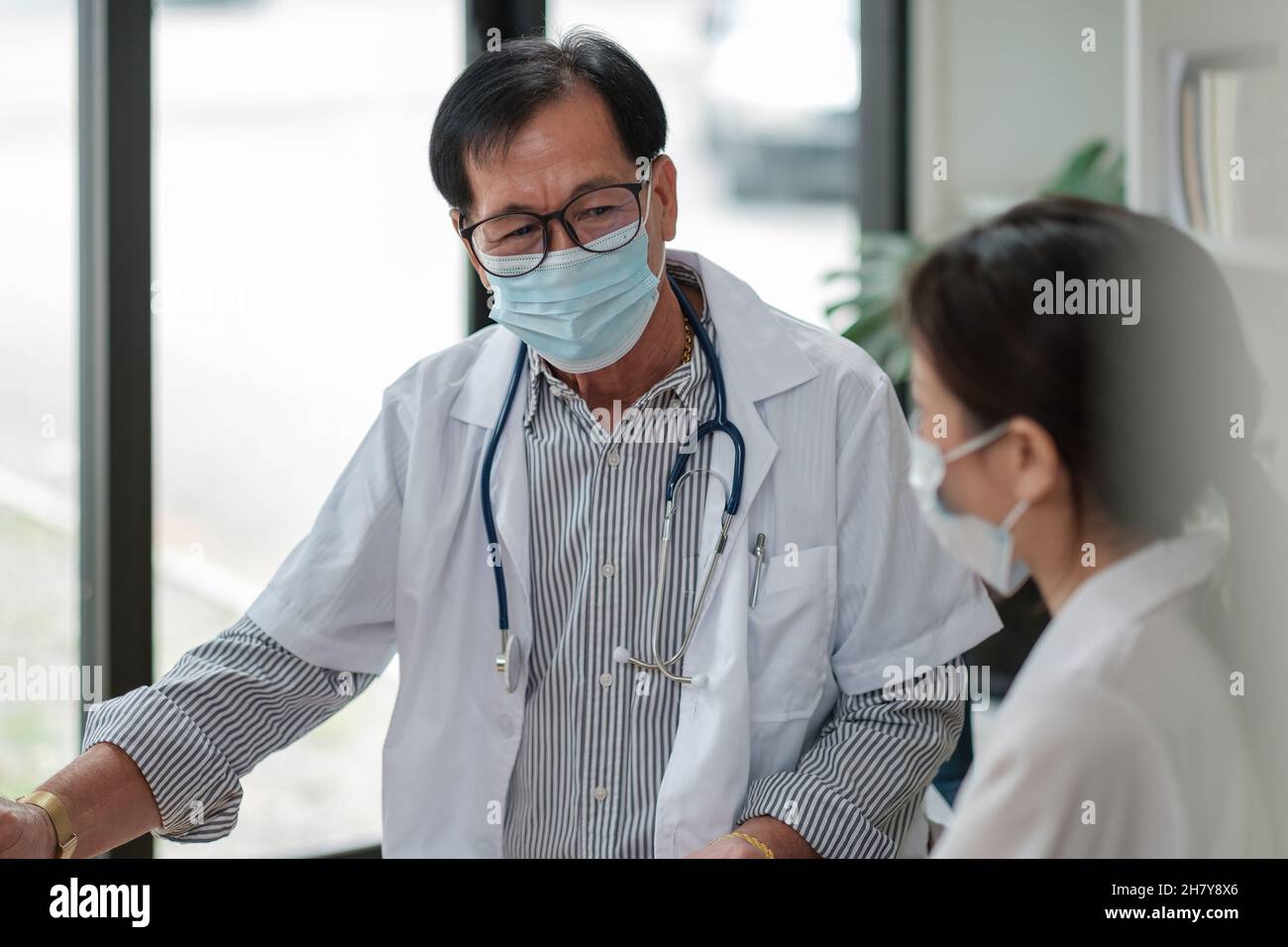 Senior doctor wearing safety protective mask supporting and cheering up ...