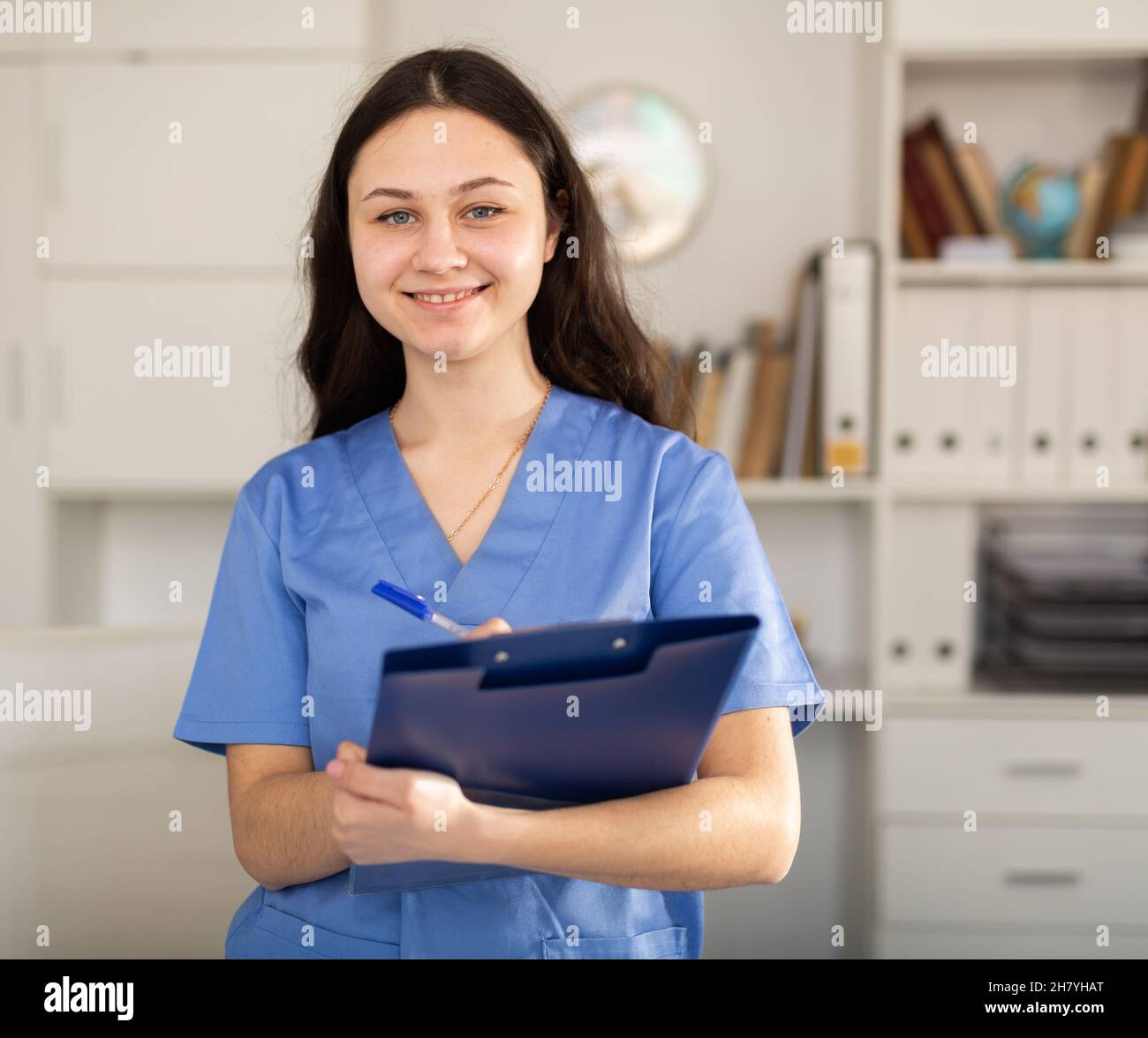 Portrait of friendly female doctor wearing uniform with folder Stock ...