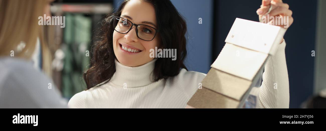 Smiling sales assistant shows samples with fabrics Stock Photo - Alamy