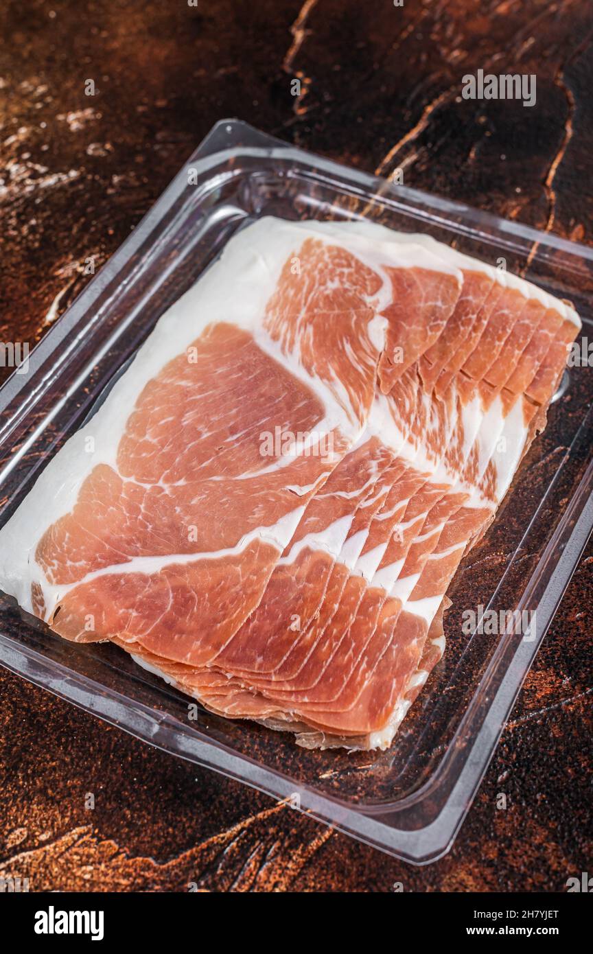 Italian prosciutto crudo or jamon in a vacuum package. Dark background ...