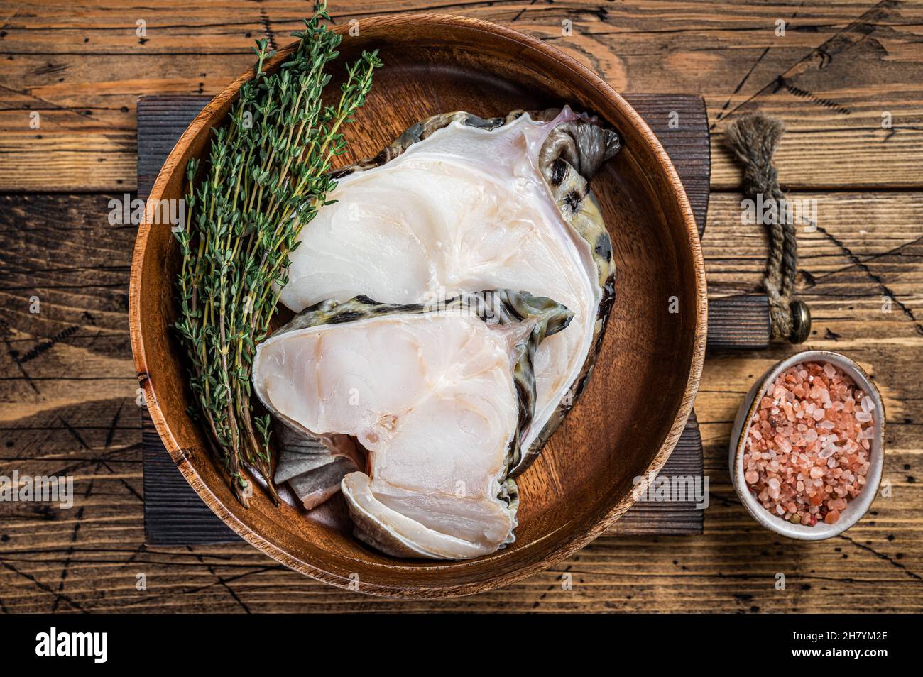 Raw wolffish or wolf fish fillet in a wooden plate. wooden background ...