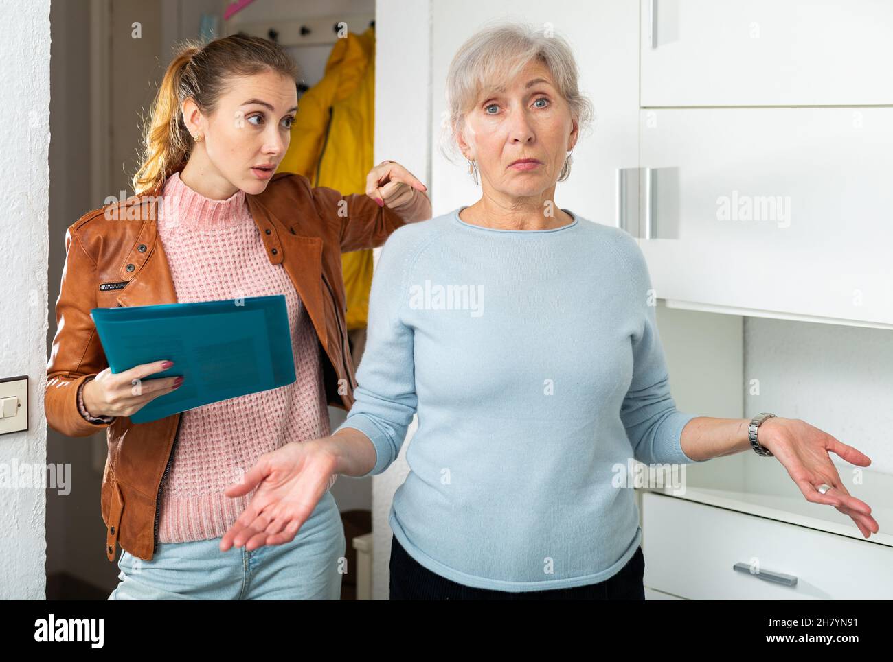 Female debt collector talking annoyed to worried elderly woman at home ...
