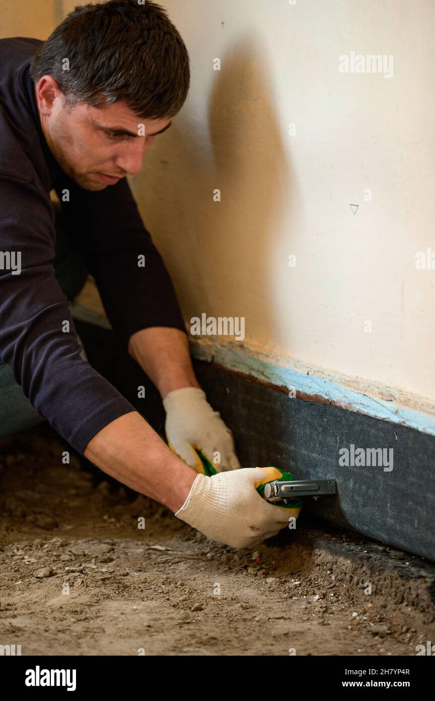 Installing waterproofing in a private house on the floor, a man ...