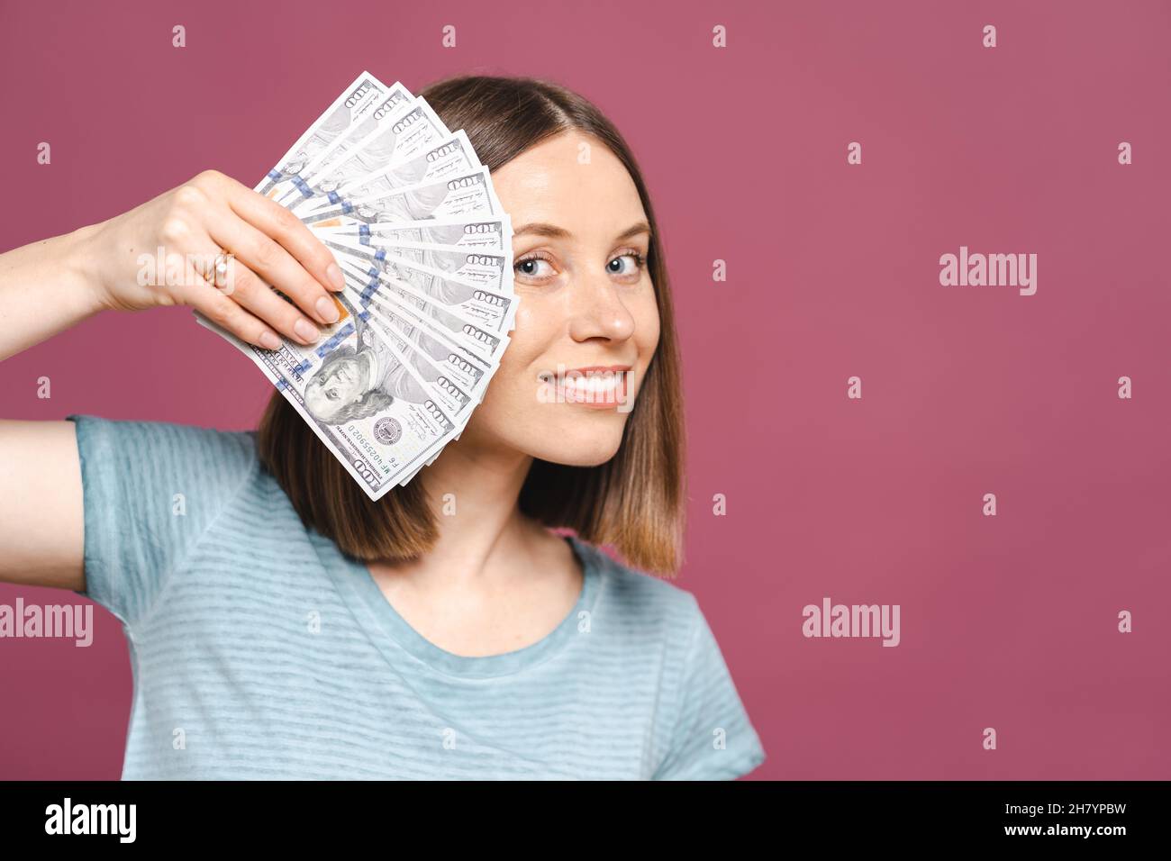 Funny young lady in a blue summer tshirt is holding money and looking ...