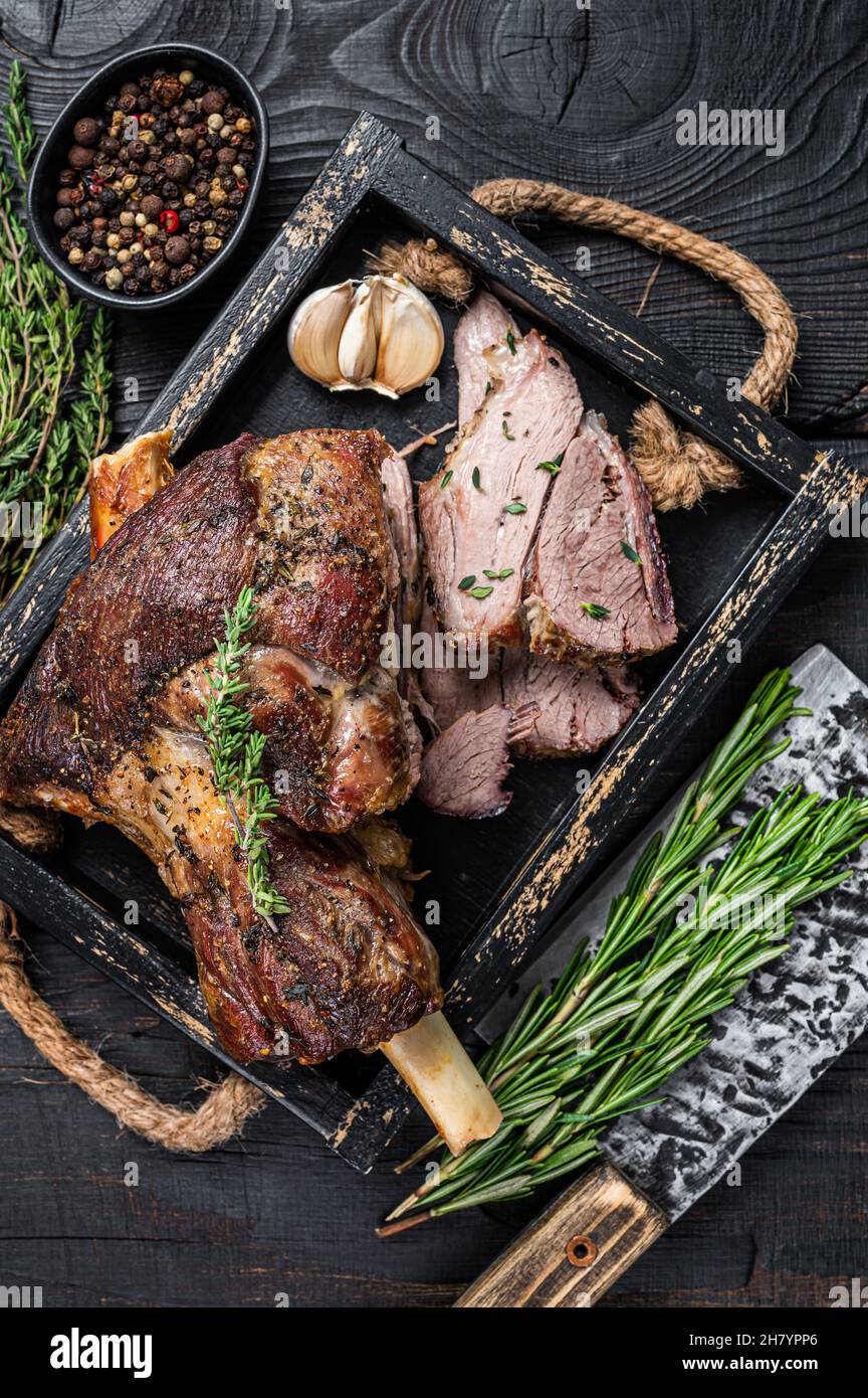 Roasted mutton lamb leg sliced in a wooden tray with meat cleaver ...