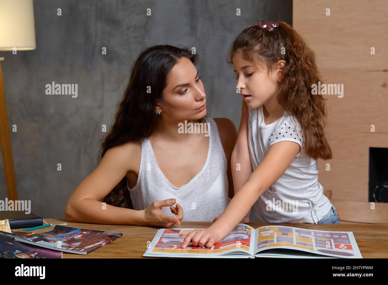 Portrait of a mother helping her small sweet and cute daughter to make ...