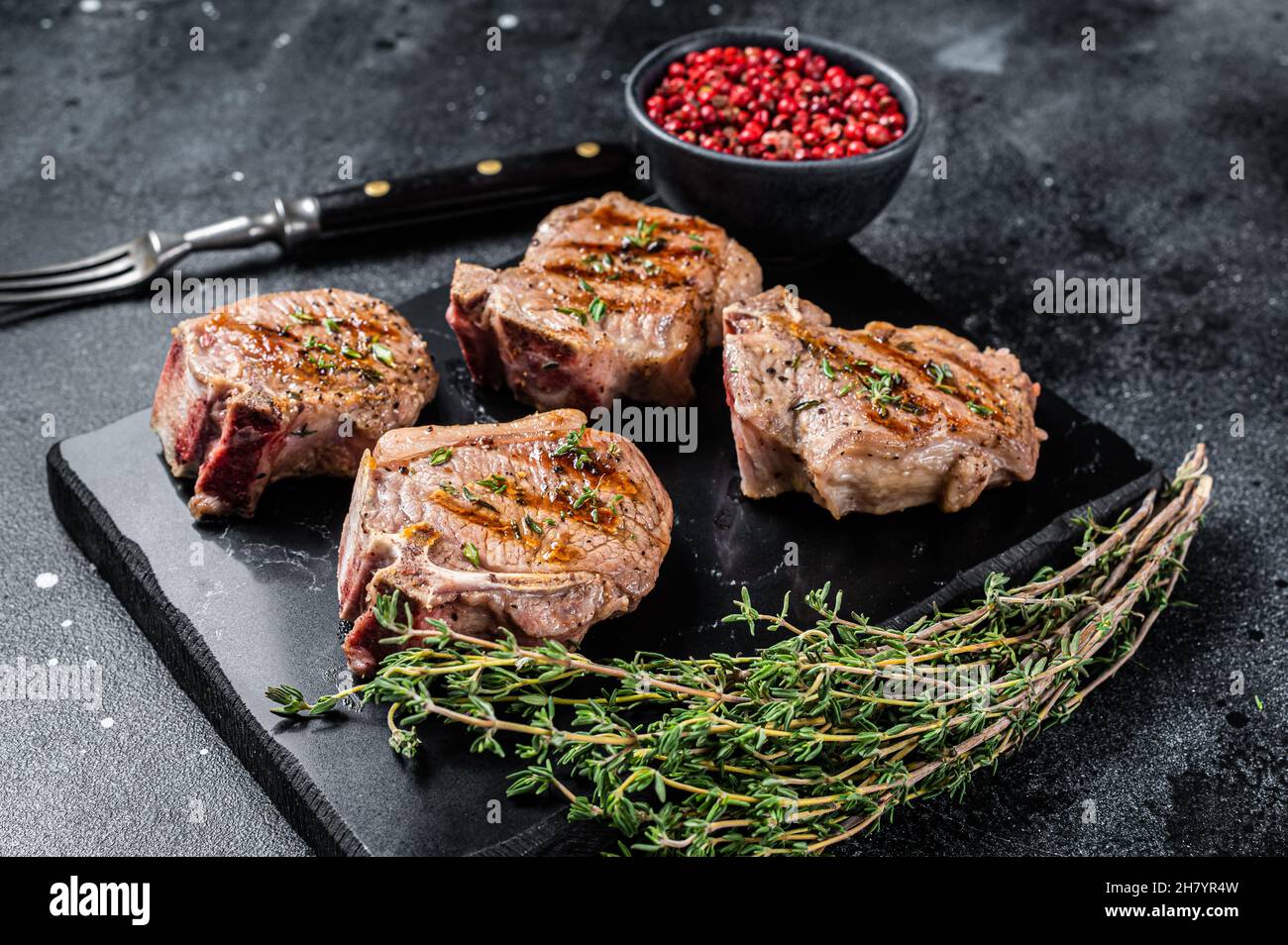 Grilled lamb loin chops steaks, cutlets on a marble board. Black ...