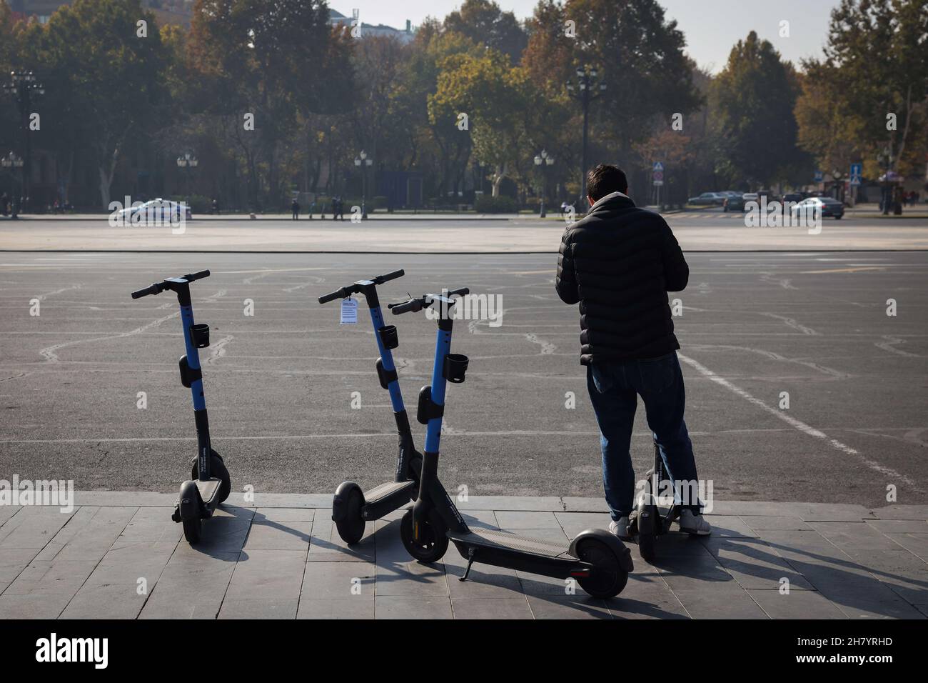 Jerewan, Armenia. 14th Nov, 2021. A young man stands next to electric scooters on Republic ...