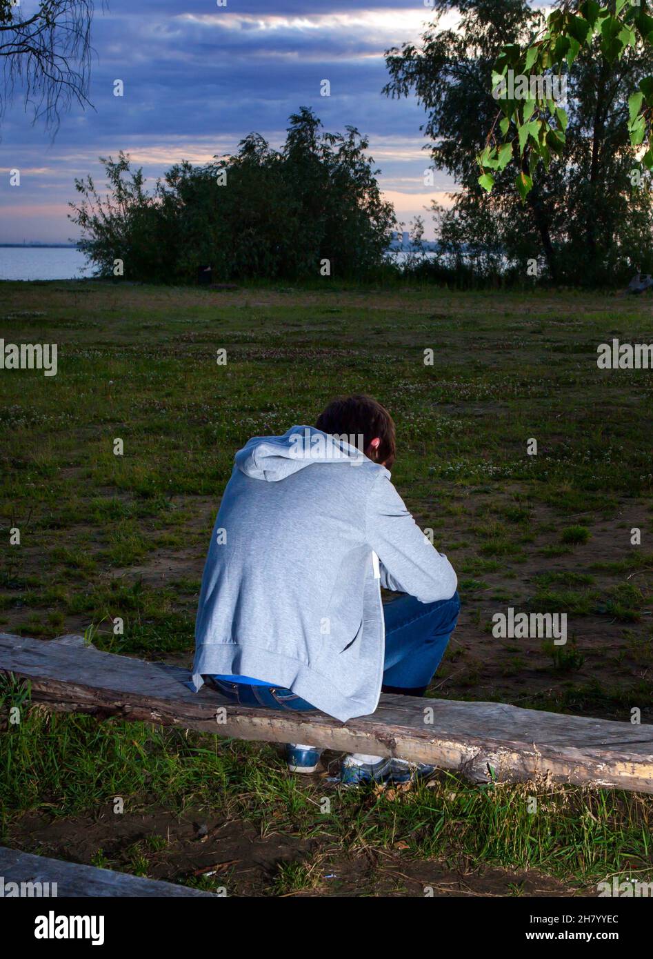 Sad Young Man sit on the Log outdoor Stock Photo - Alamy