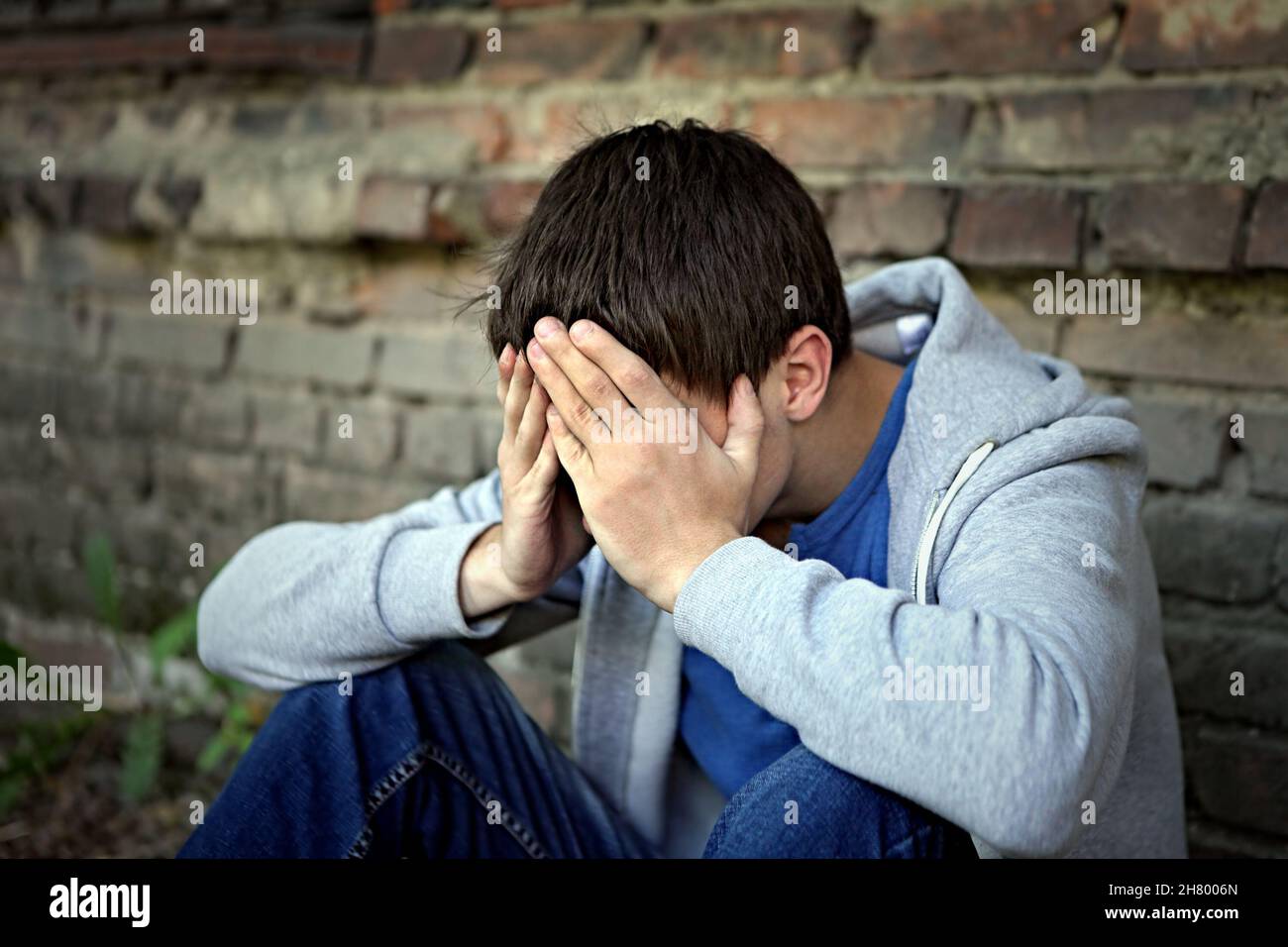 Sad Young Man sit on the Brick Wall Background Stock Photo - Alamy