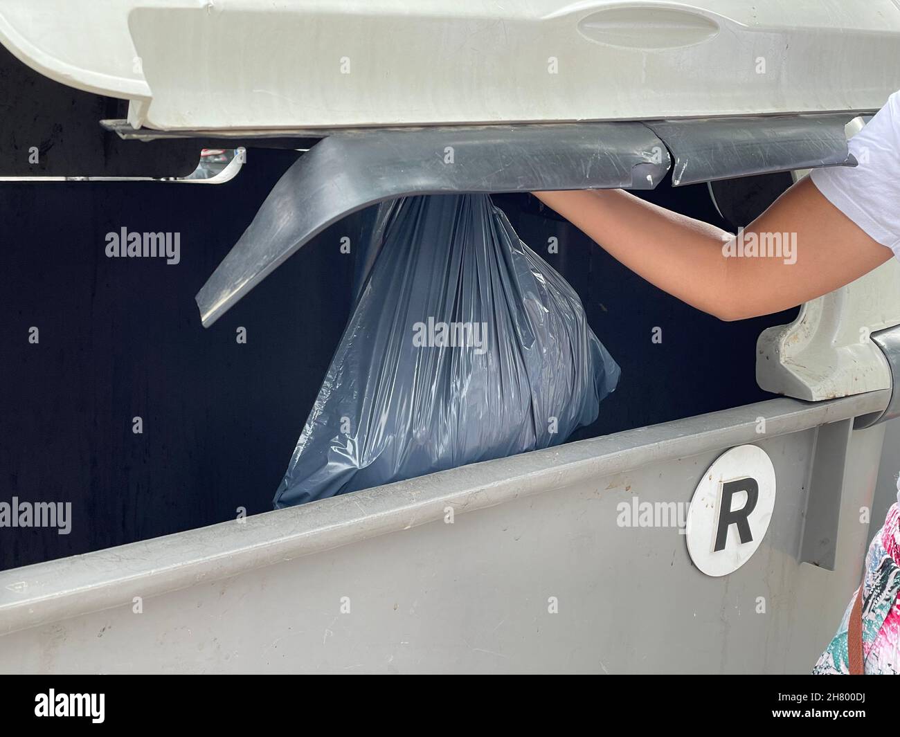 hands of a woman throughing trash to a dupster - sustainability and ...