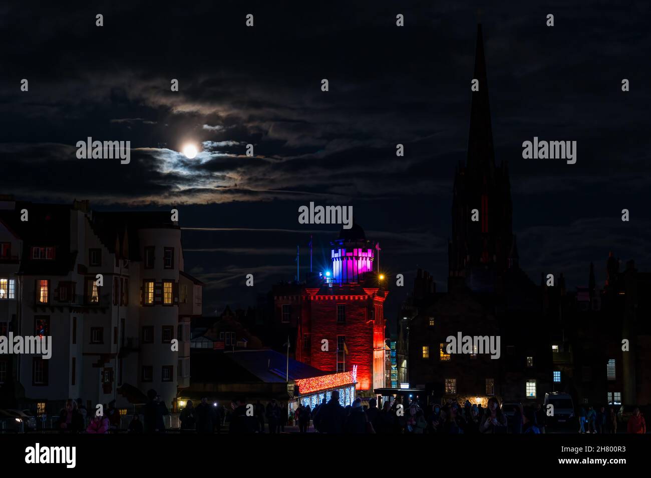 A full moon behind clouds at night time seen from the Royal Mile with ...