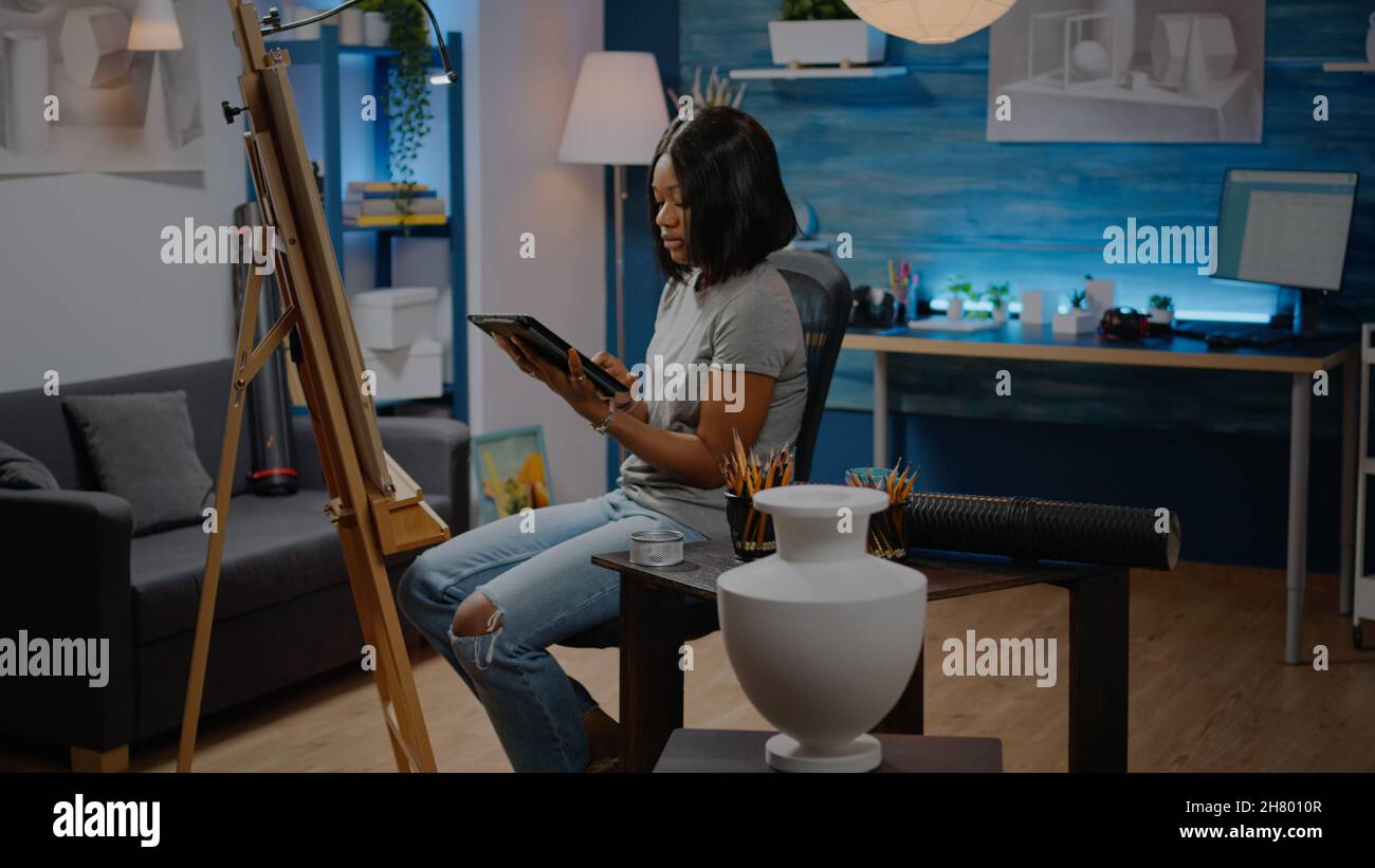 Black young artist holding digital tablet for vase drawing in artwork ...
