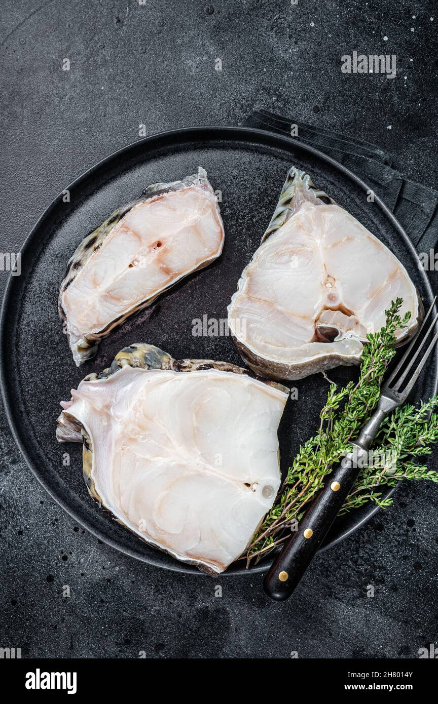 Fresh Raw wolffish o wolf fish Steak on a plate. Black background. Top ...