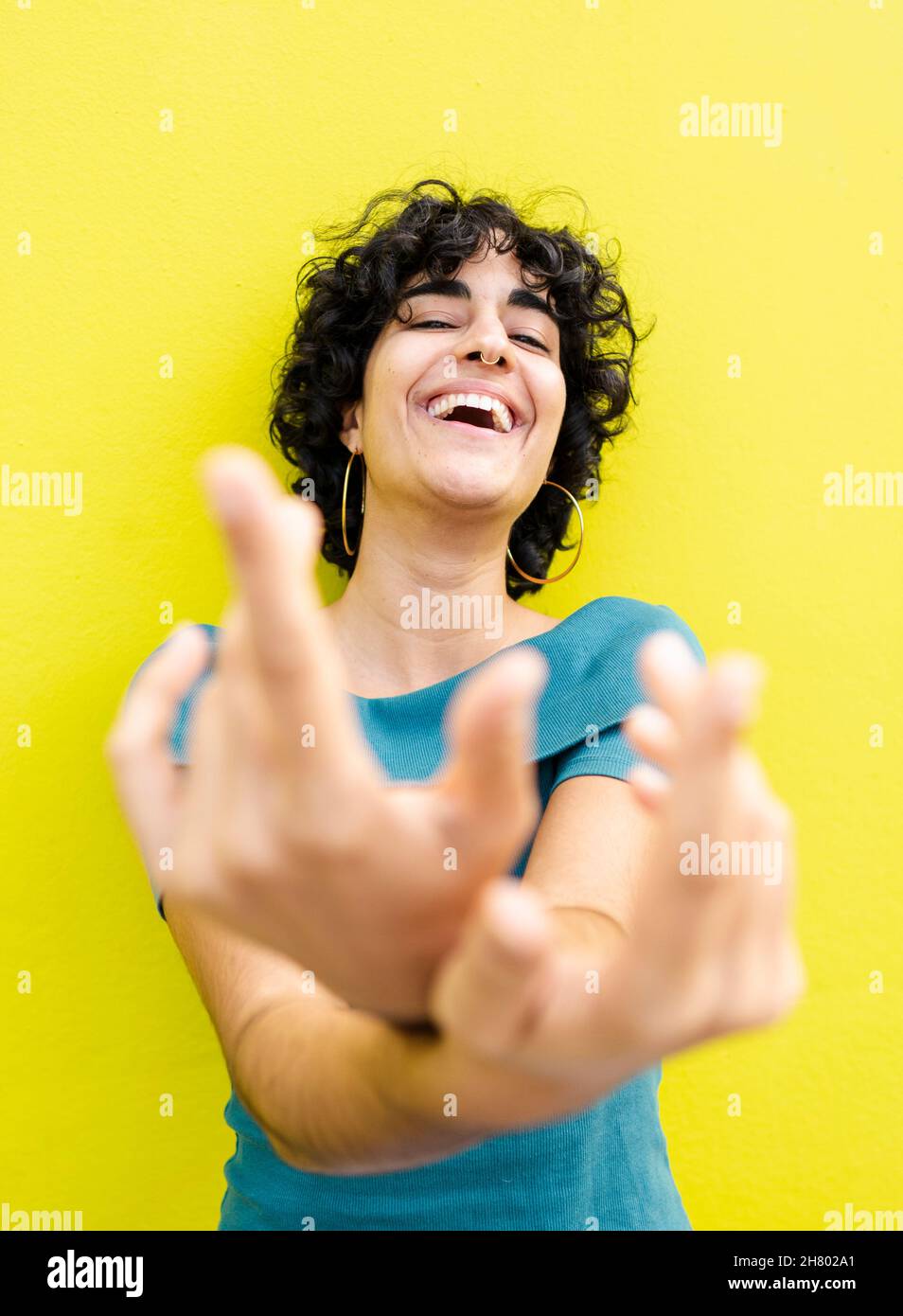 Cheerful curly haired female laughing with opened mouth and reaching ...