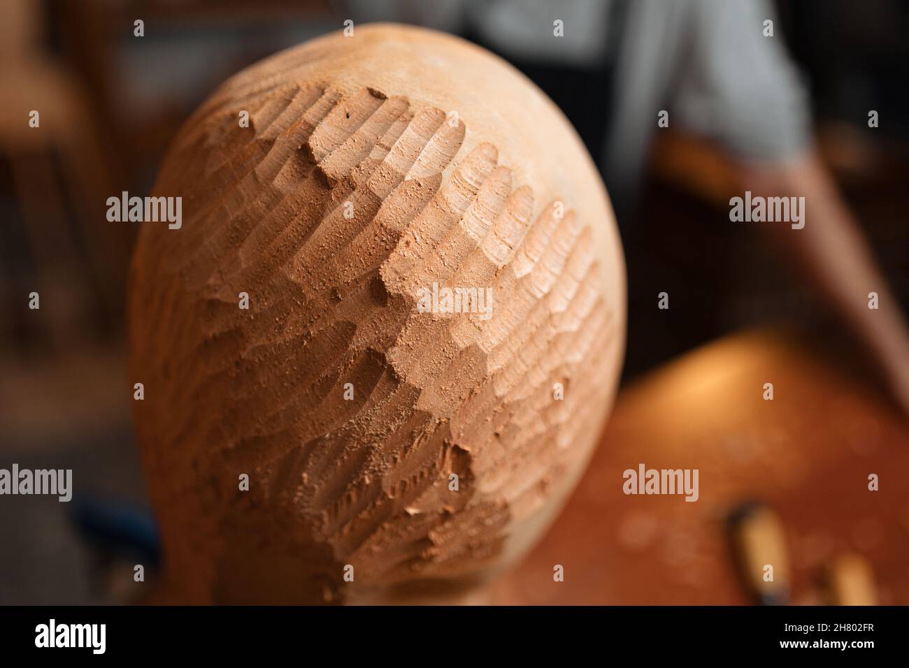 Round shaped carved piece of wood on table with tools in light ...