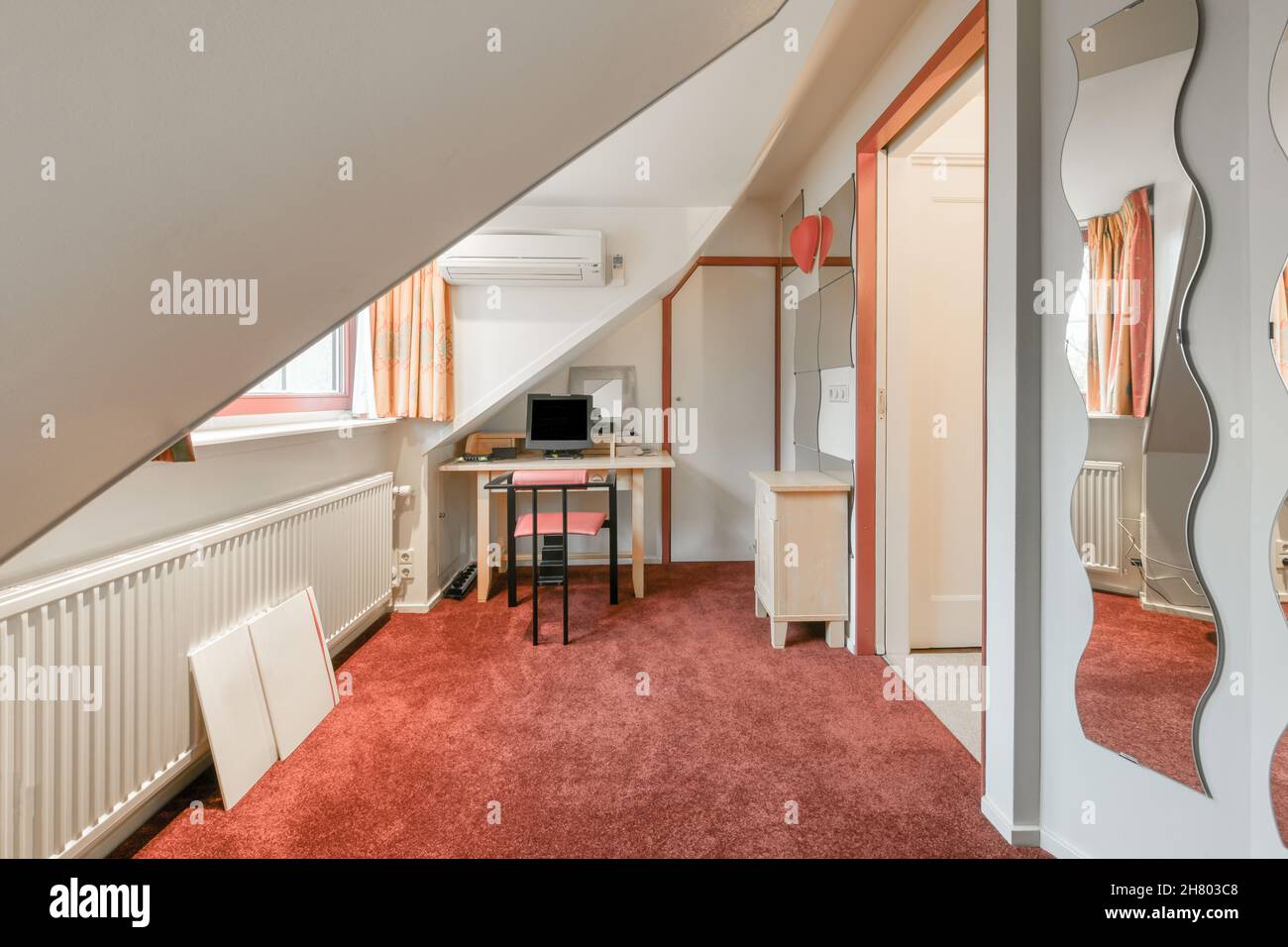 Chair and table with computers near TV set in corner placed opposite to ...