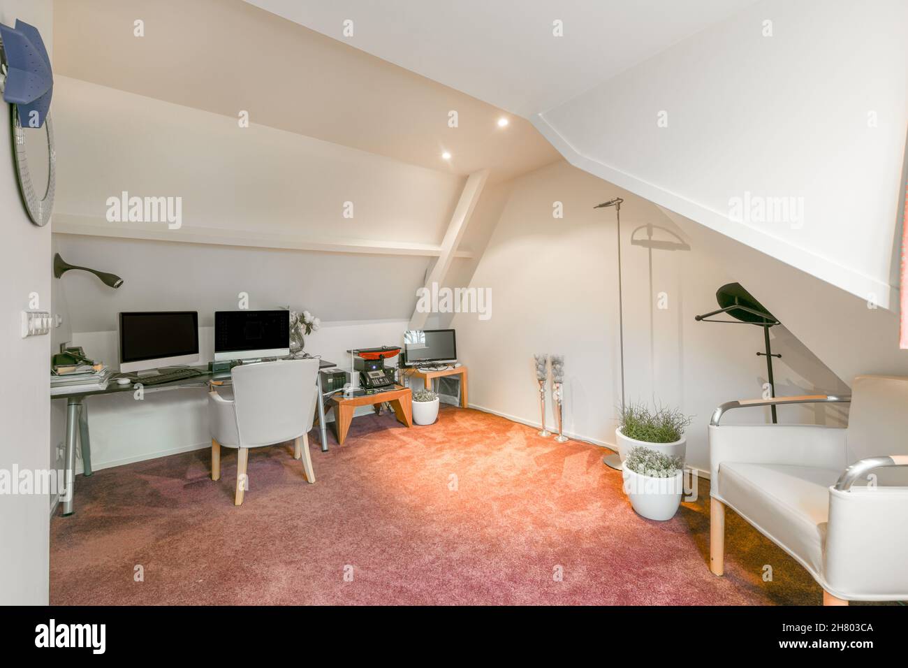 Chair and table with computers near TV set in corner placed opposite to ...