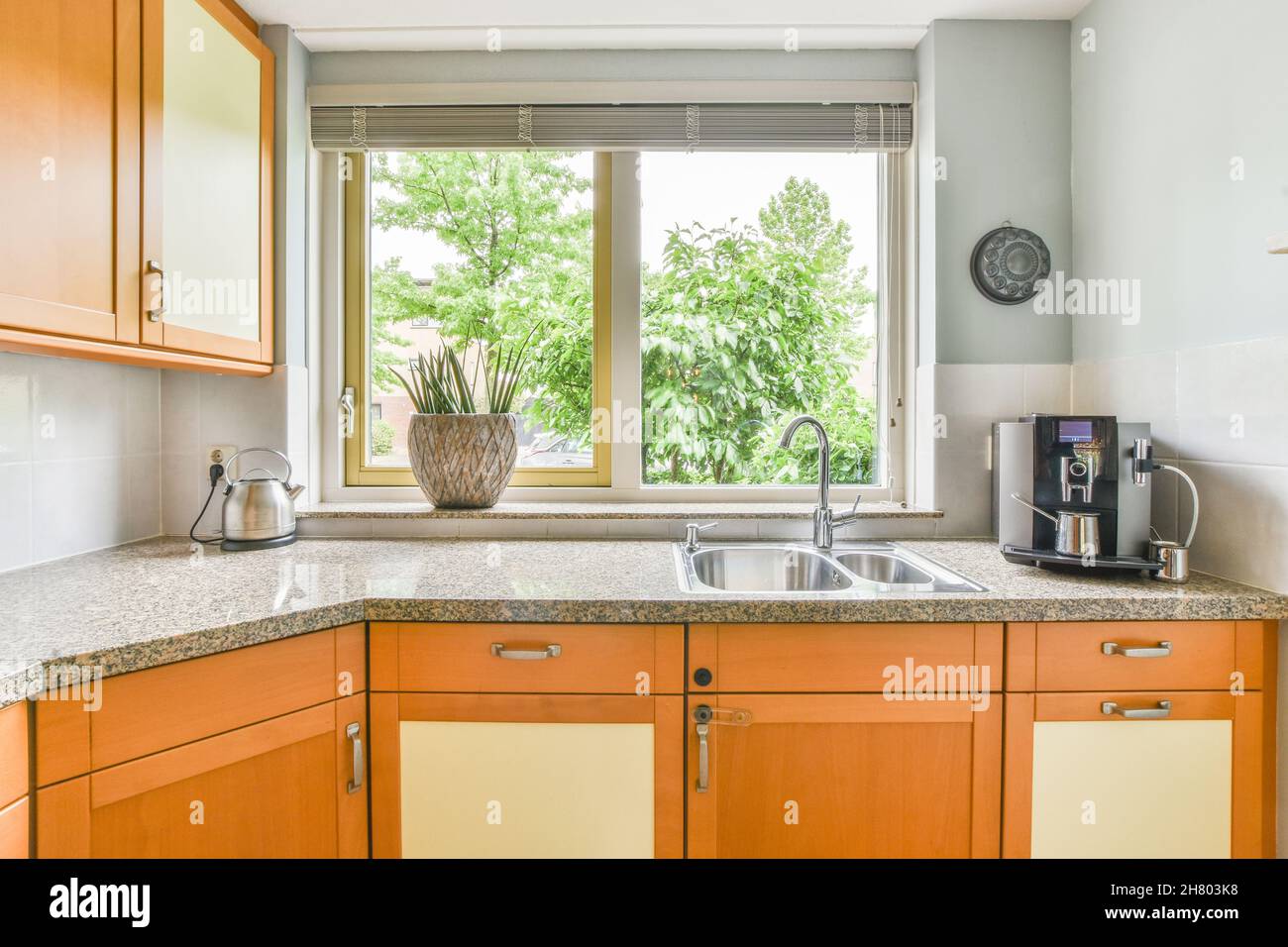 Wooden cabinets and counter with stove near window in light stylish ...