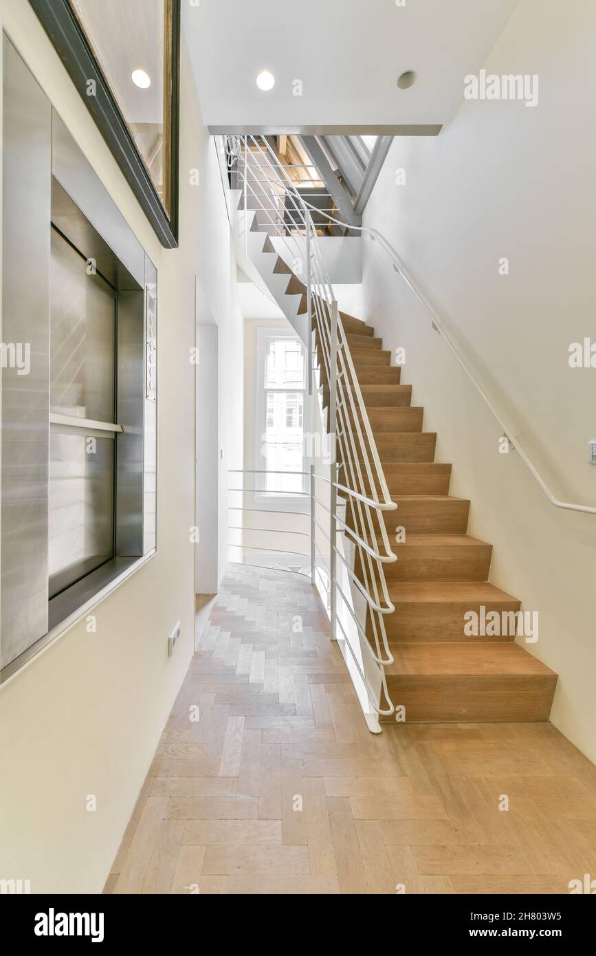 Long stairway with wooden steps and metal railings placed in corridor ...