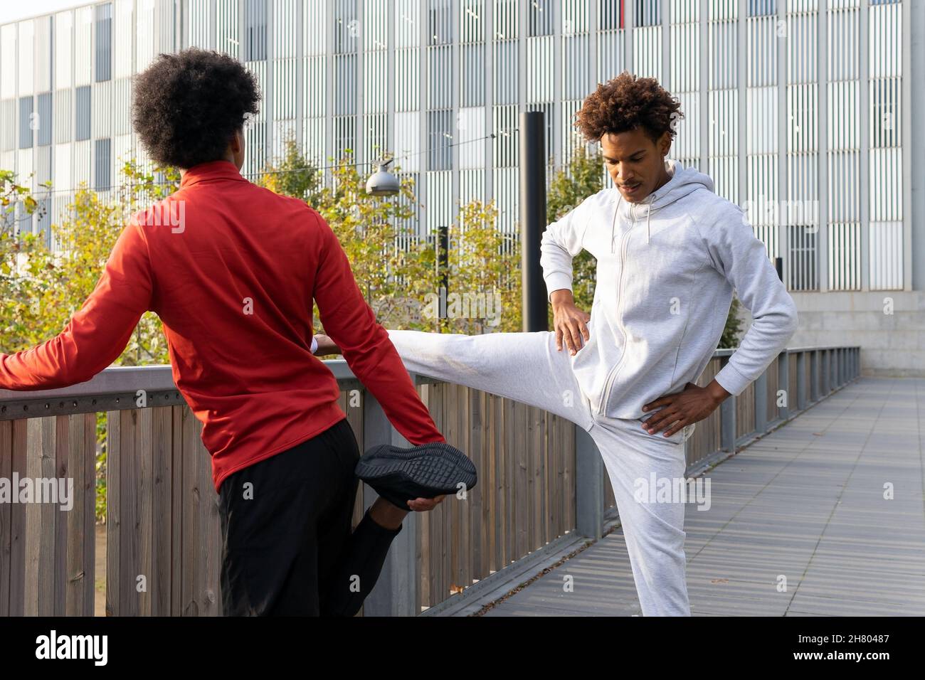 Side view of African American male doing legs stretch with leg on ...