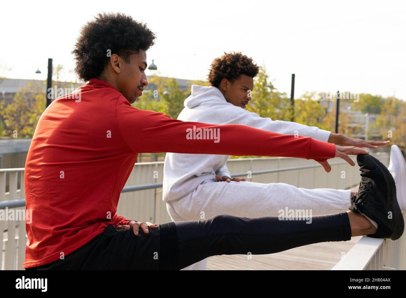 Side view of African American male doing hamstring stretch with leg on ...