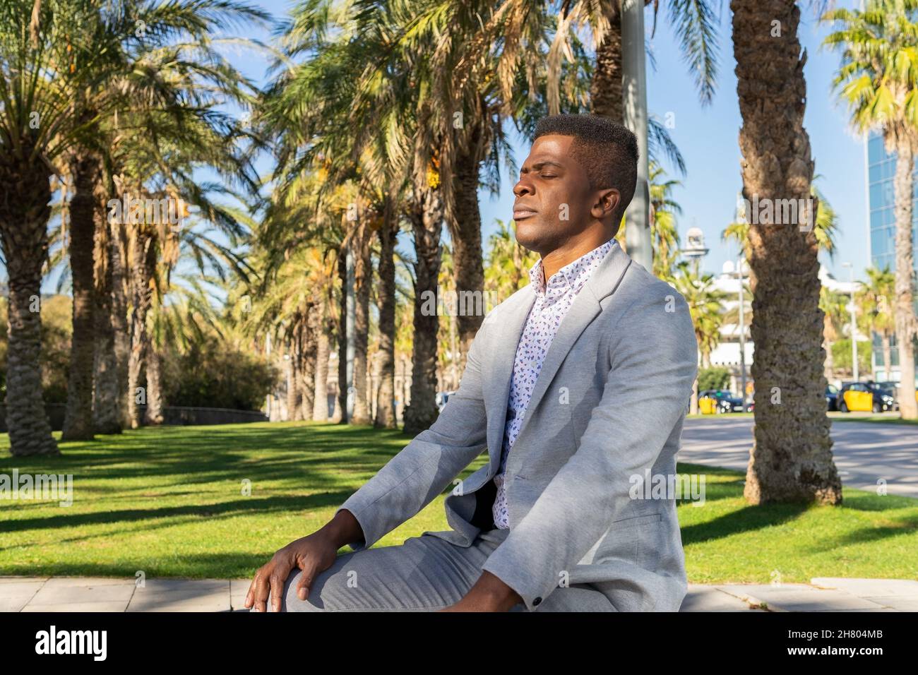 Serene African American male with closed eyes in formal wear meditating ...