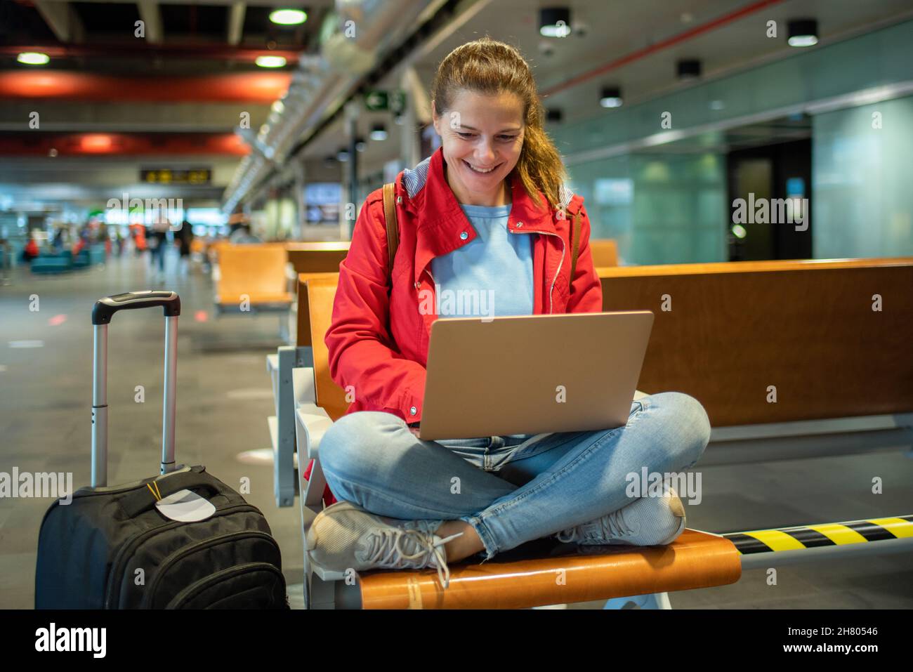Full body of positive female traveler typing on modern netbook while ...