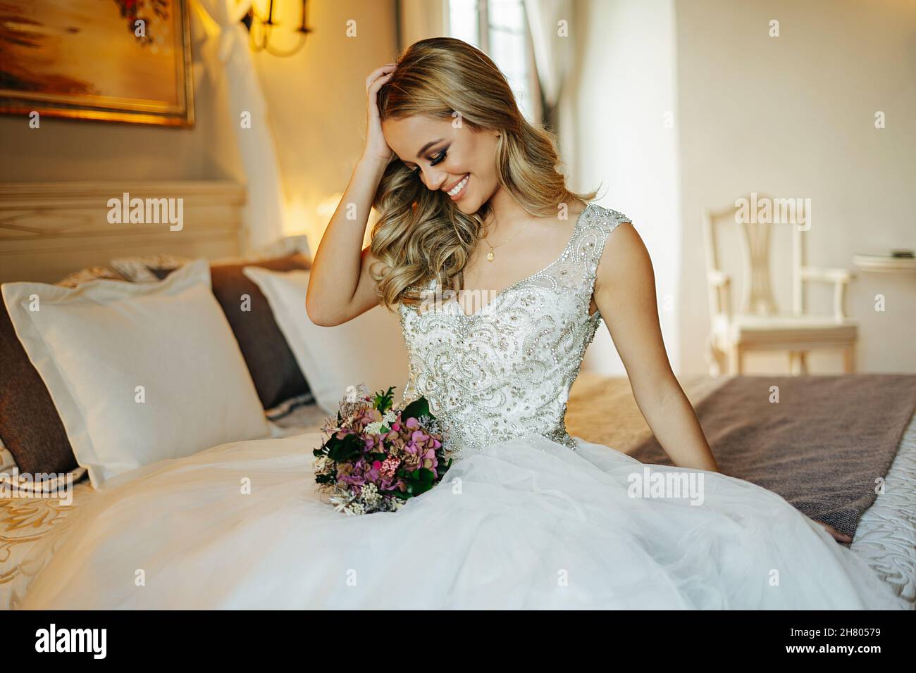 Cheerful bride in elegant wedding dress with bouquet of fresh flowers ...