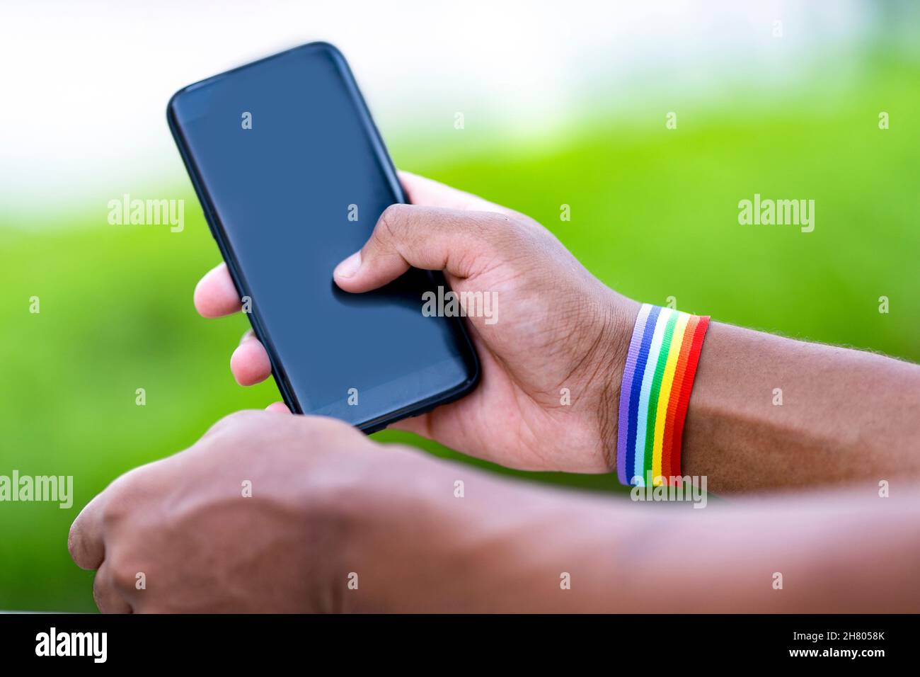 Crop anonymous African American male with LGBT rainbow bracelet using ...