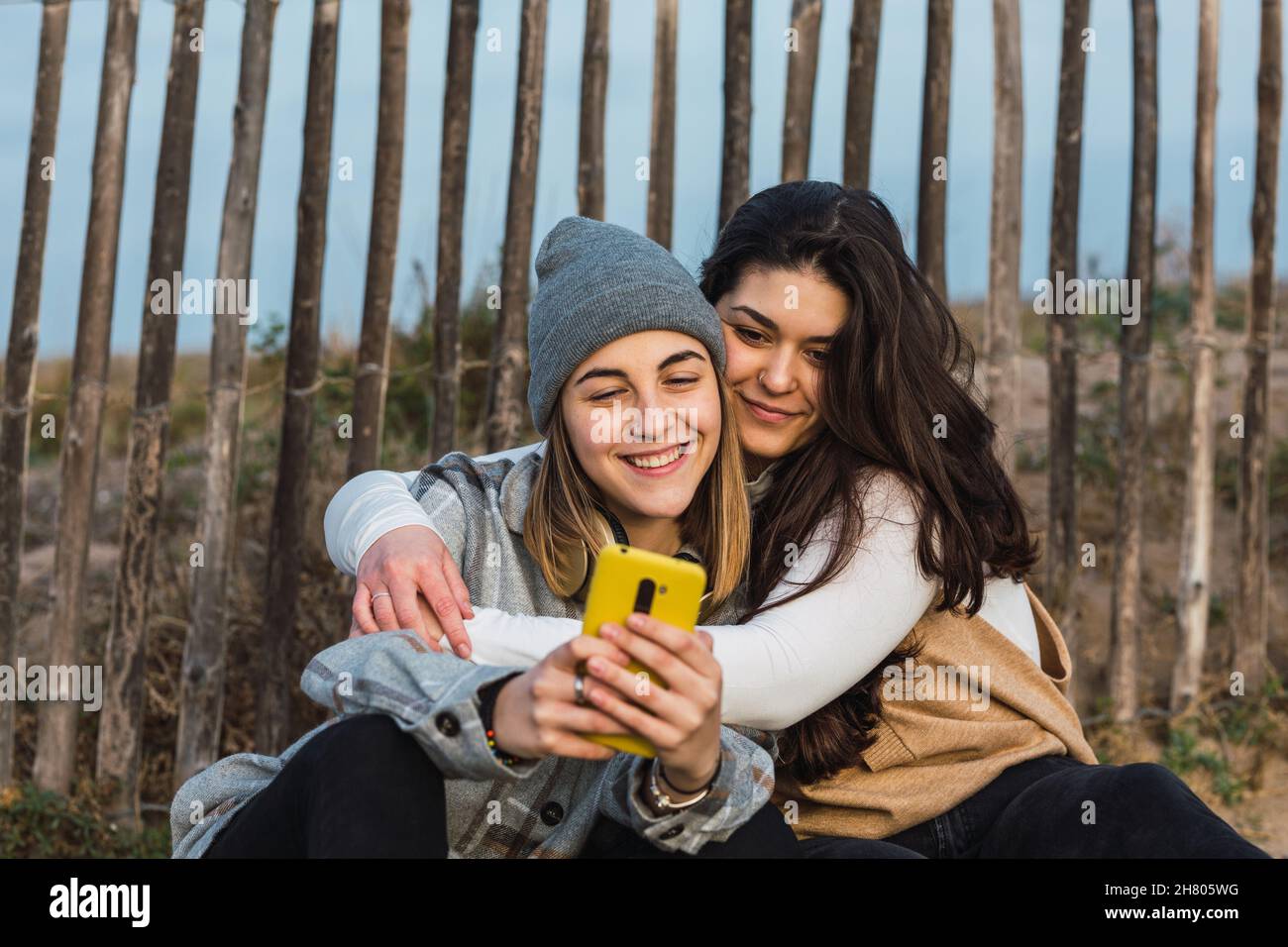 Young lady with long dark hair in casual clothes sitting on wooden path ...