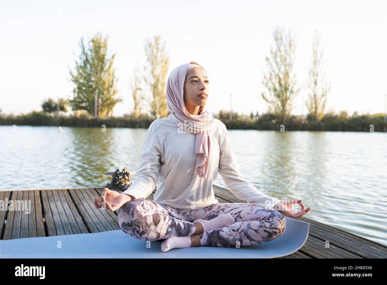 Full body of peaceful Arab female sitting in Lotus pose on mat near ...