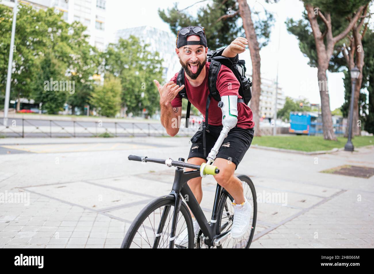 Funny male hipster with artificial arm showing shaka gesture and tongue ...