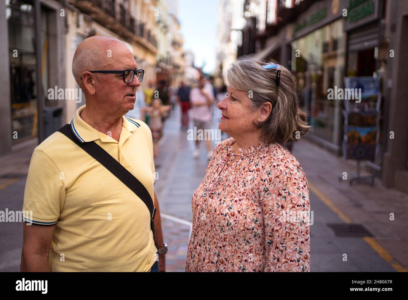 Mature couple of tourists in casual wear looking at each other while ...