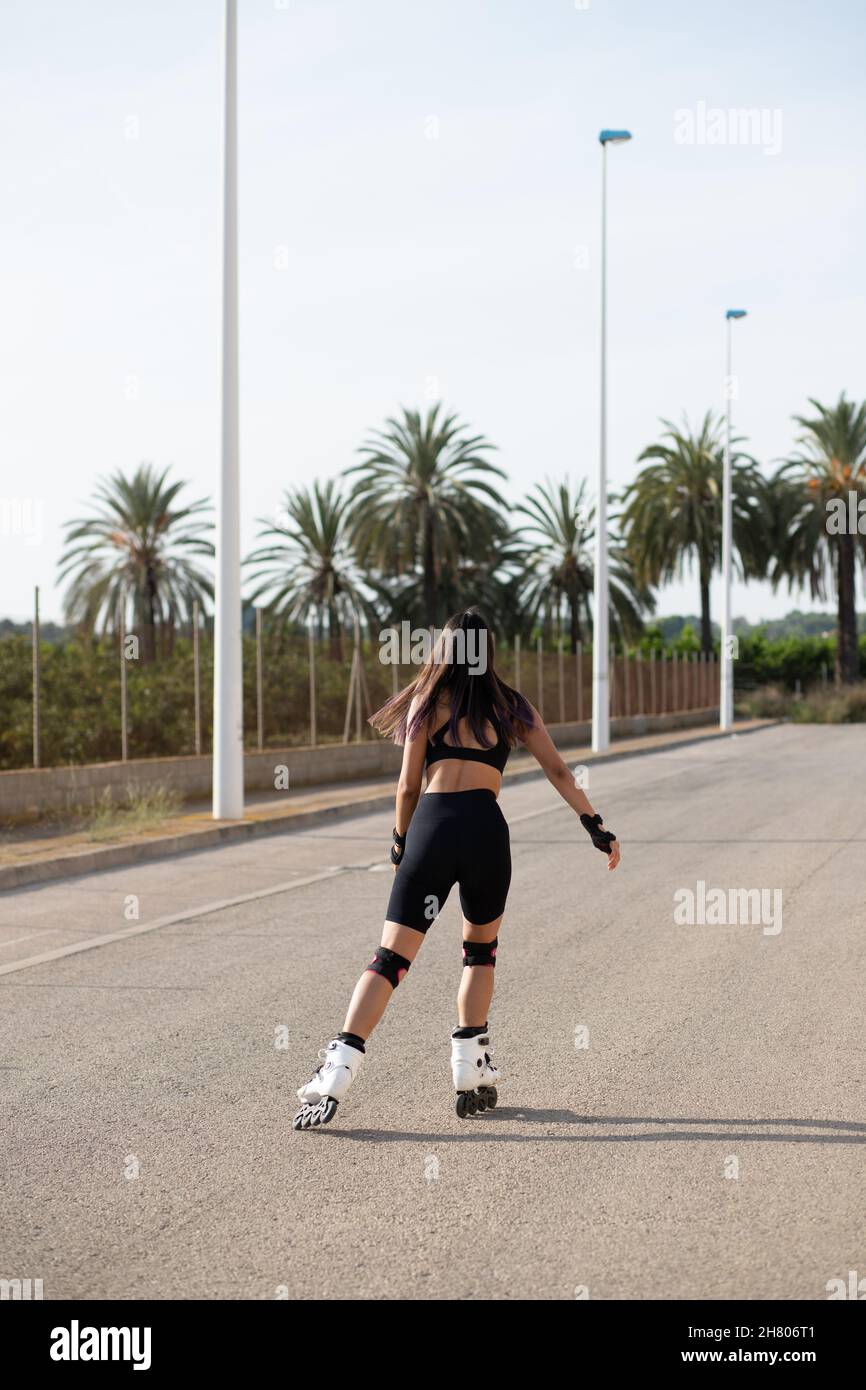 Full body back view of anonymous fit female in sportswear roller ...