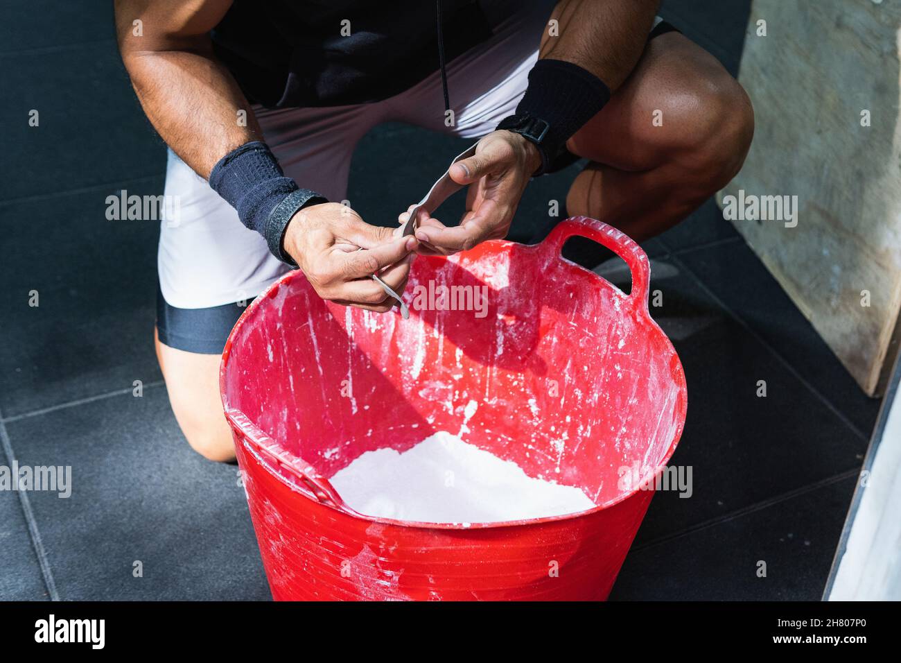 Crop anonymous sportive male in sportswear hunkering down near red ...