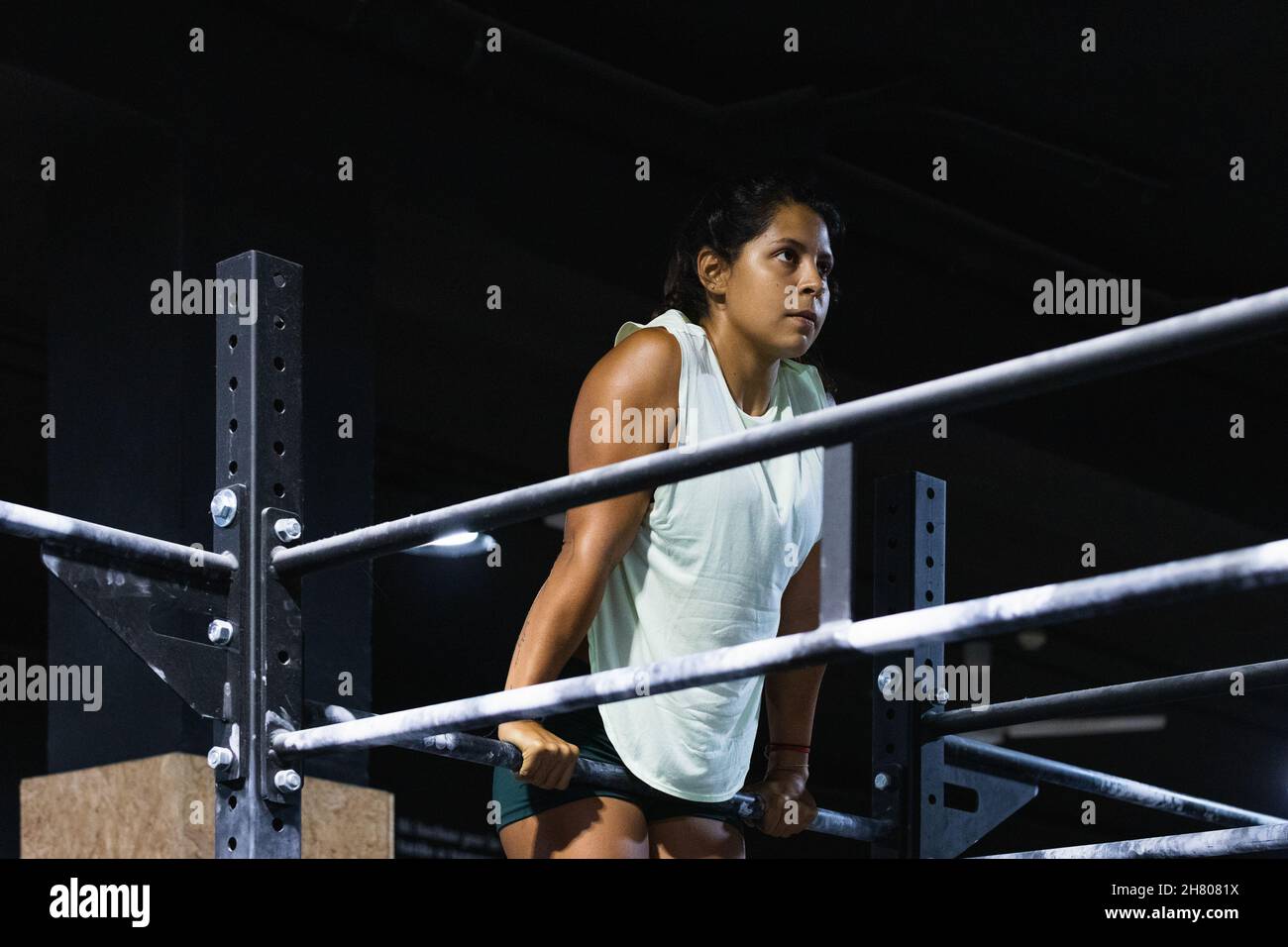 Strong Hispanic female athlete in sportswear doing exercise on metal ...