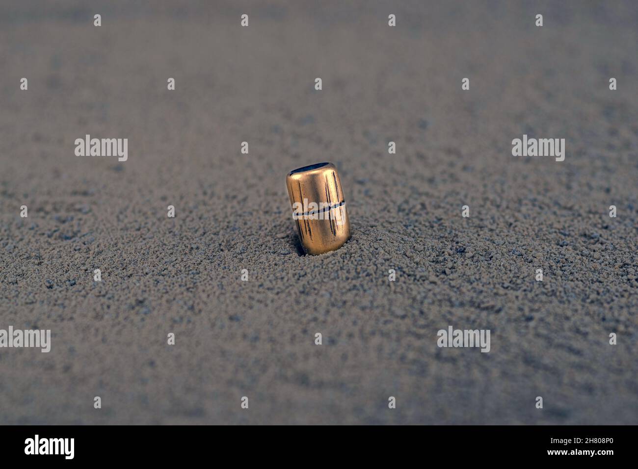 An old shiny bullet driven into the sand in macro mode Stock Photo - Alamy