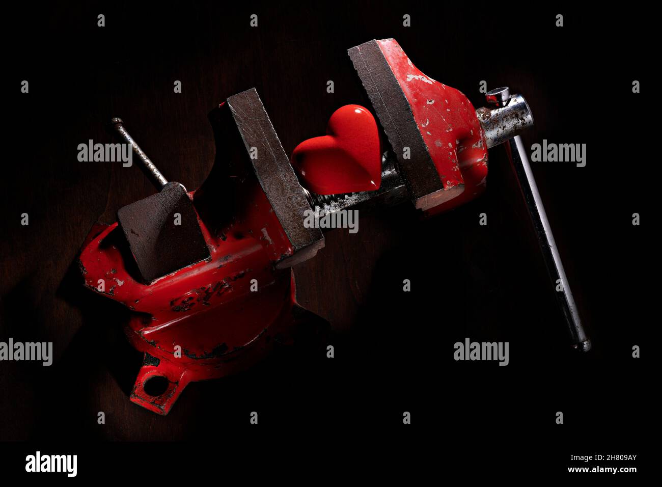 red heart clamped in a vice Stock Photo - Alamy