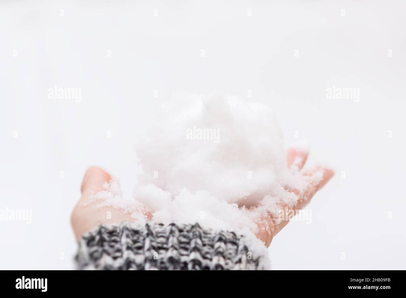 Snow hand close-up. A woman's hand in a gray sweater holds a lump of ...