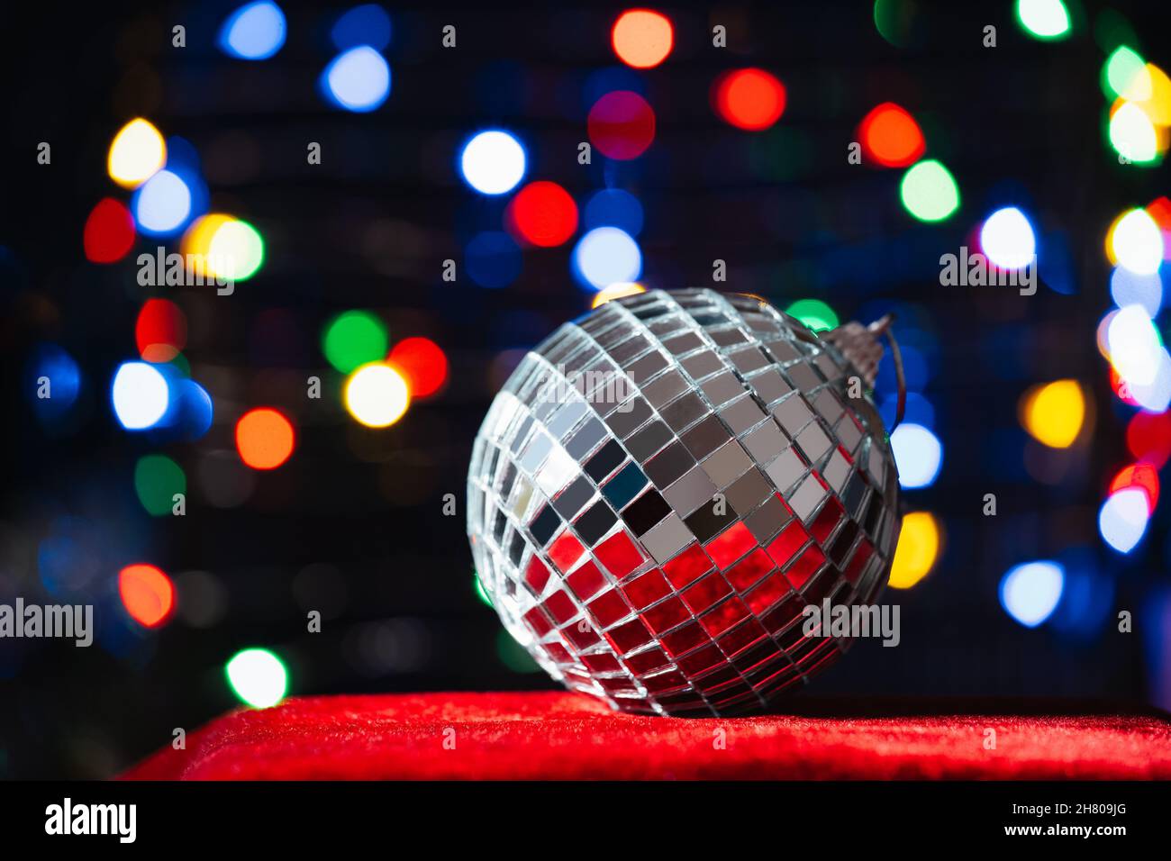 silver disco ball on red velvet podium with multicolor fairy string ...
