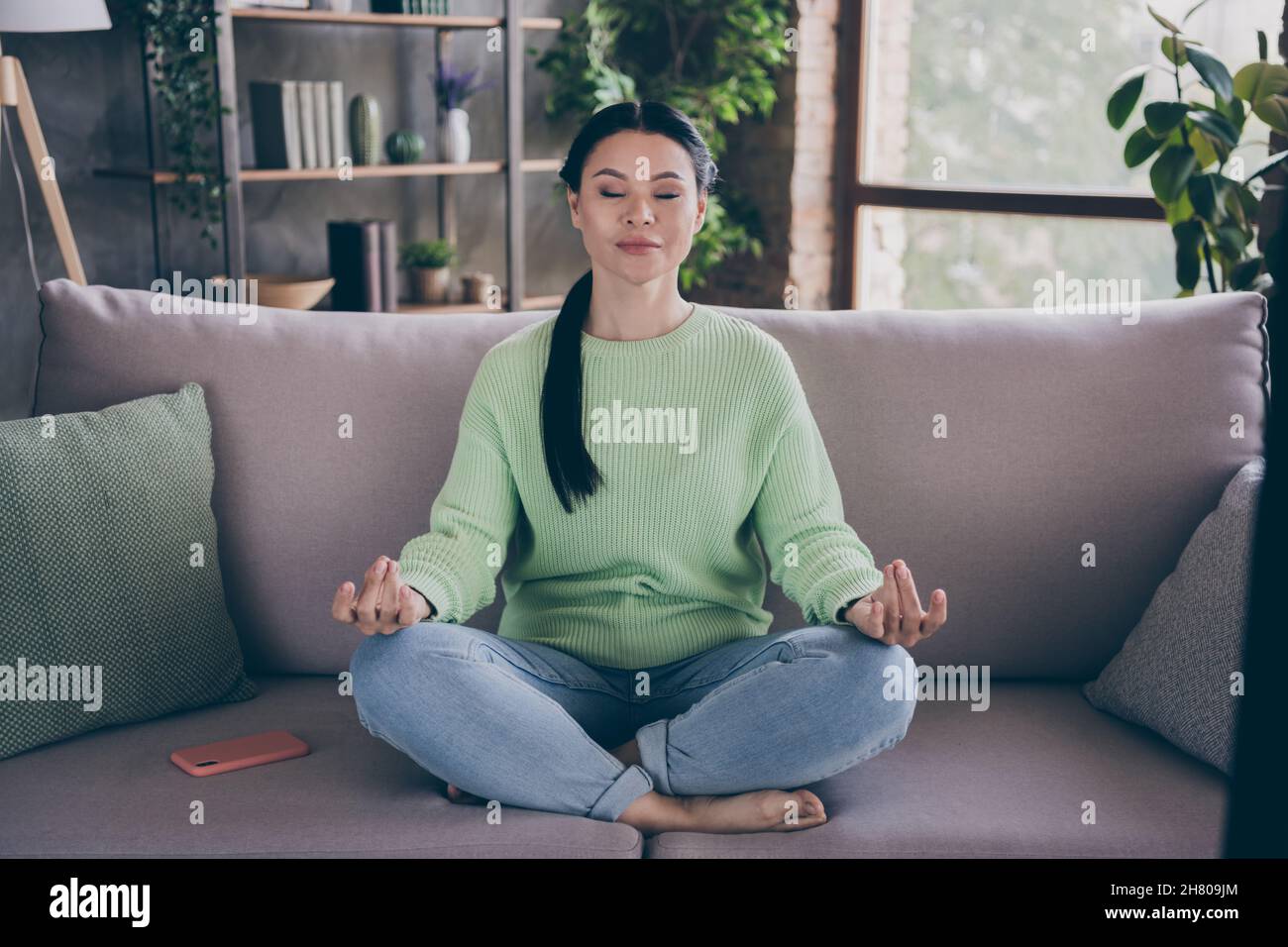 Full length photo of lovely mature woman sitting divan flat lotus pose ...