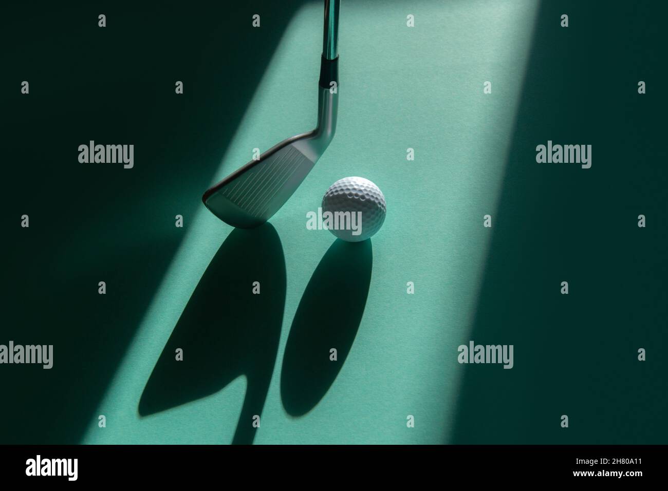 White golf ball and stick with natural lighting on mint background ...