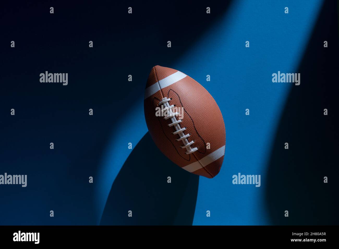 American football ball with natural lighting on blue background ...