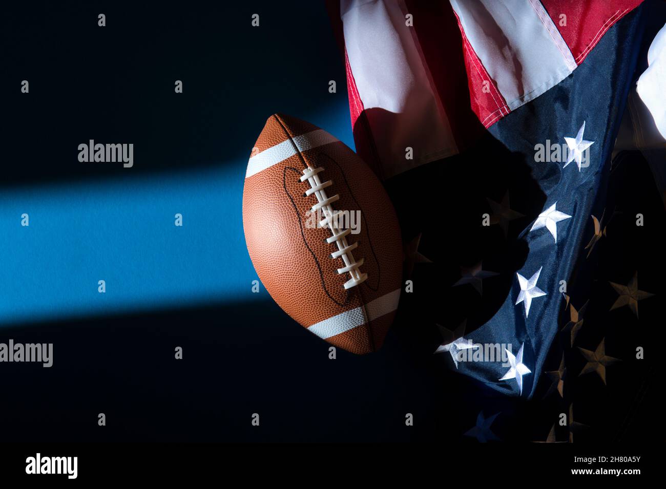 American football ball and flag with natural lighting on blue ...