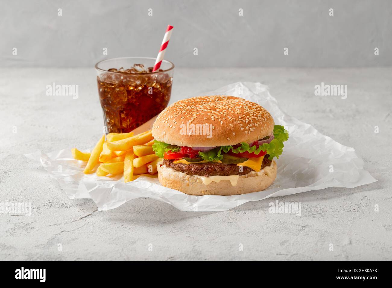 Classic cheeseburger, french fries and soda drink on gray background ...