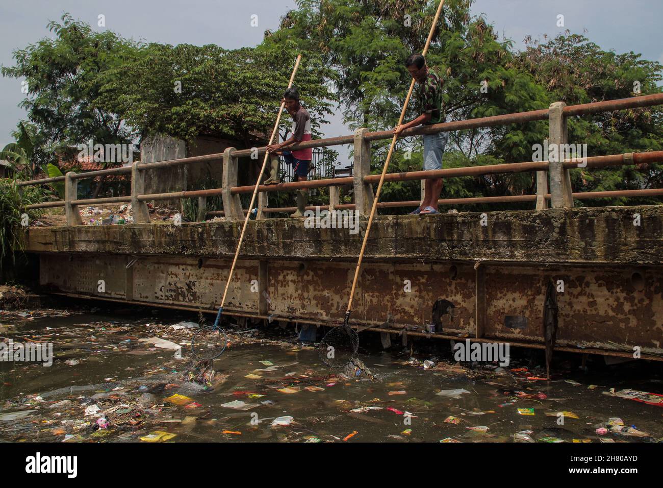 Bandung, Indonesia. 26th Nov, 2021. Men net plastic waste to let water ...