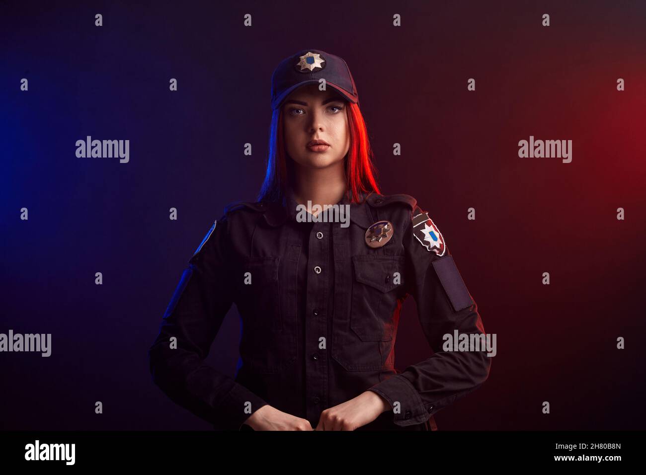 Serious female police officer is posing for the camera against a black ...