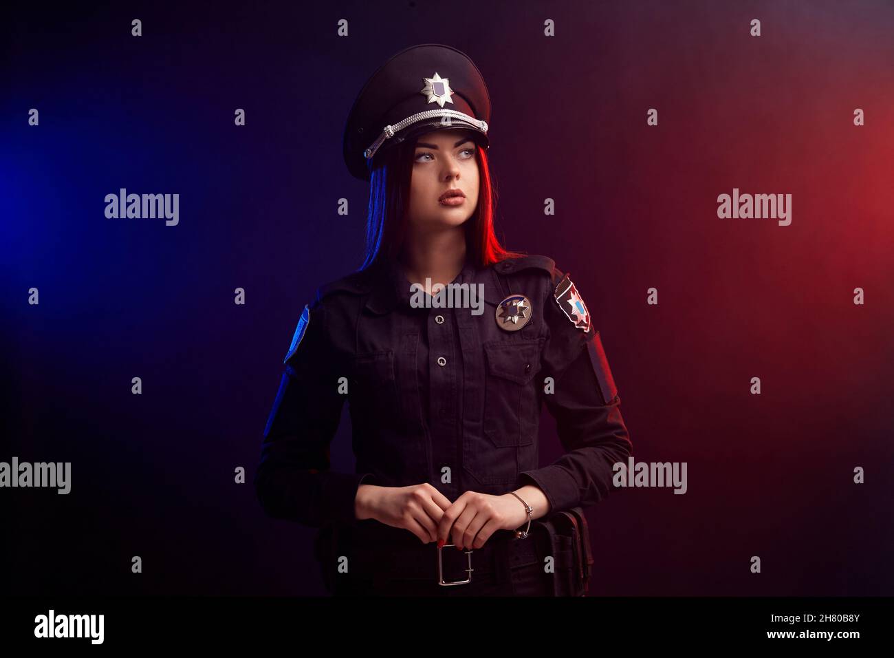 Serious female police officer is posing for the camera against a black ...